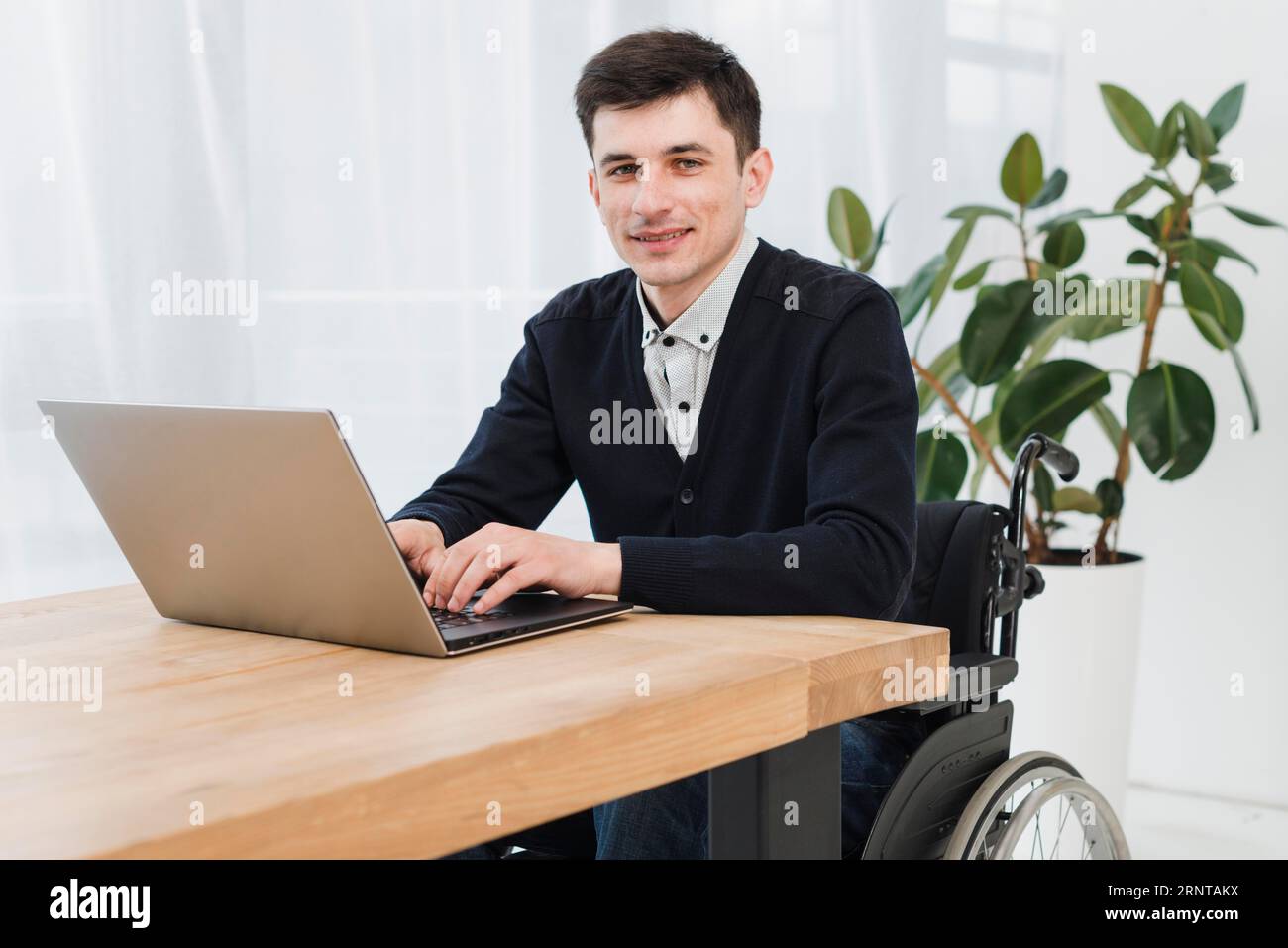 Portrait smiling young businessman sitting wheelchair using laptop Stock Photo - Alamy