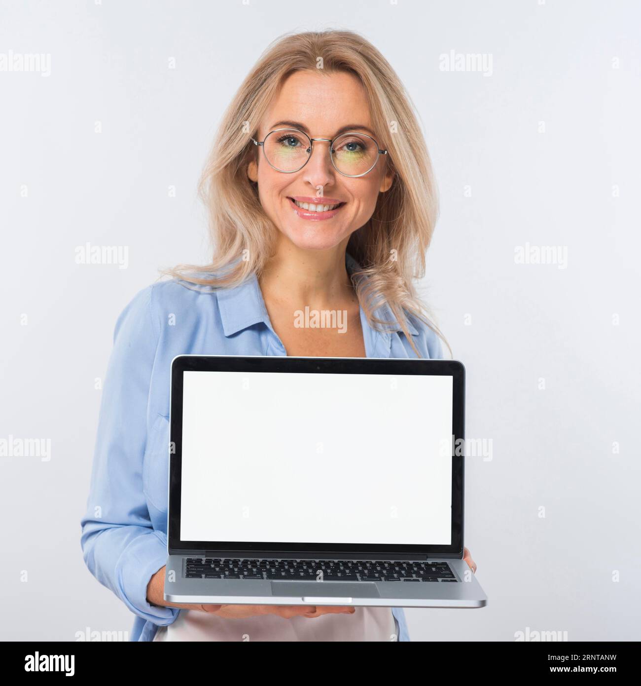 Portrait blonde young woman holding open laptop with blank screen ...