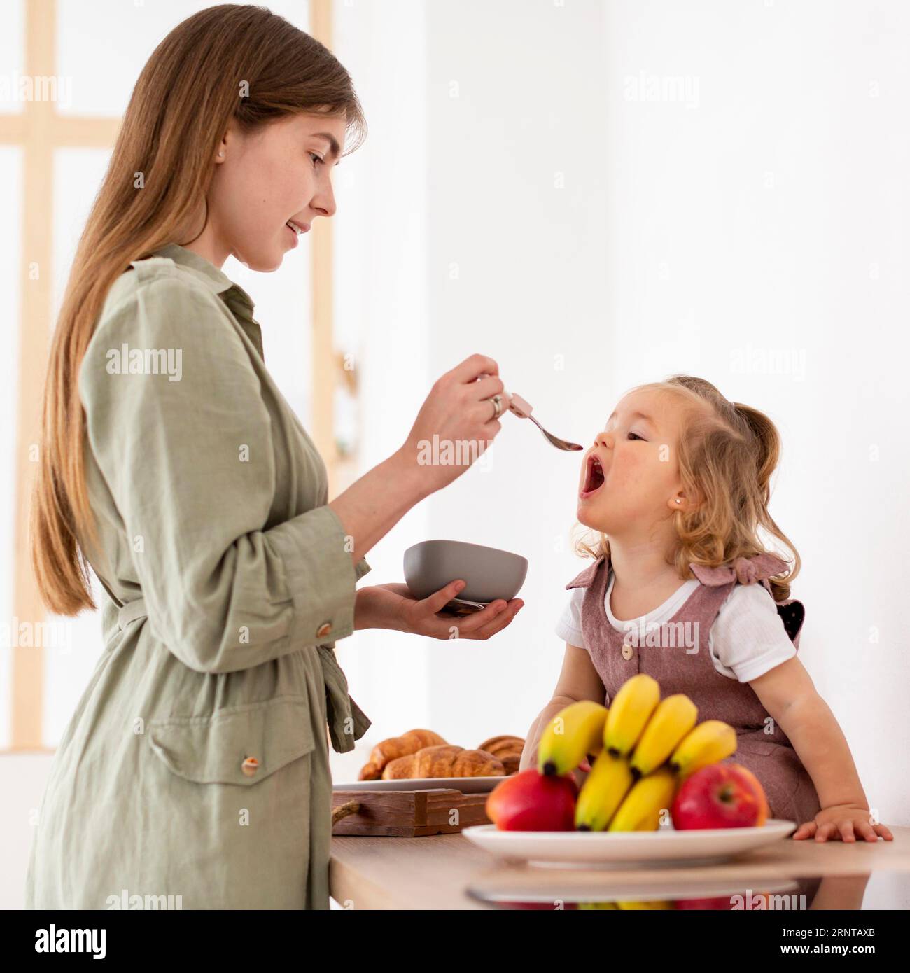 Smiley mother feeding daughter Stock Photo - Alamy