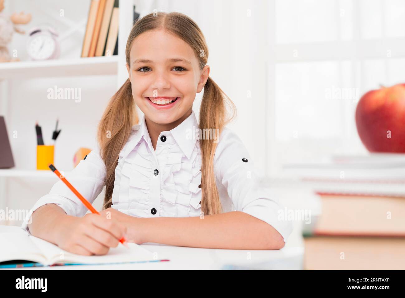 Smiling blonde elementary school girl doing homework Stock Photo - Alamy