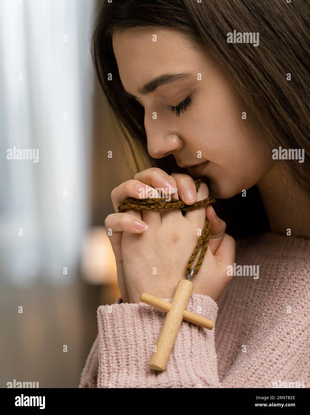 Side view woman praying while holding wooden cross Stock Photo - Alamy
