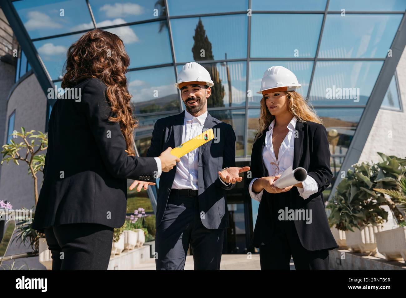 Three architects talking front glass buidling Stock Photo - Alamy