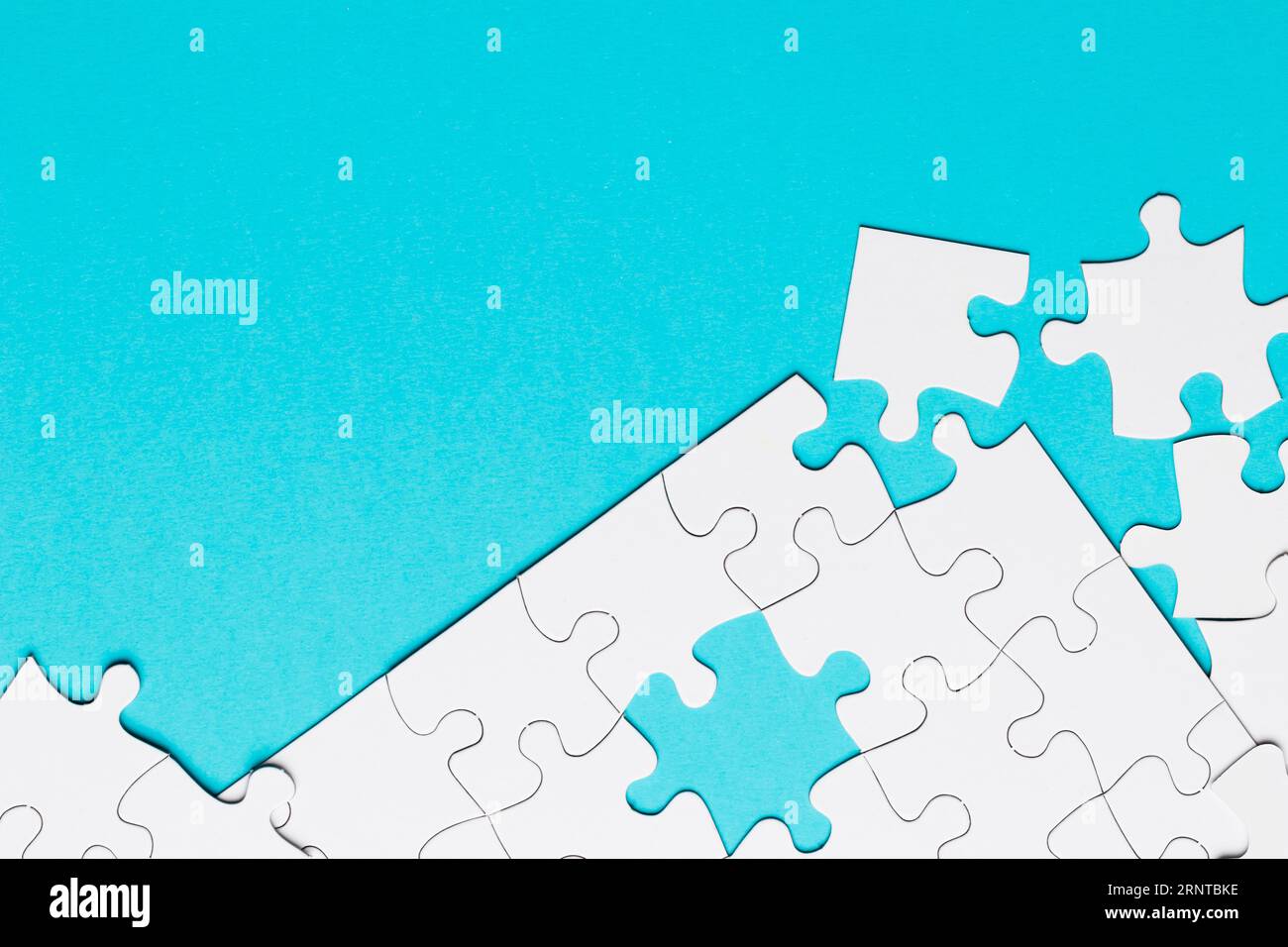 White jigsaw puzzle piece blue backdrop Stock Photo - Alamy