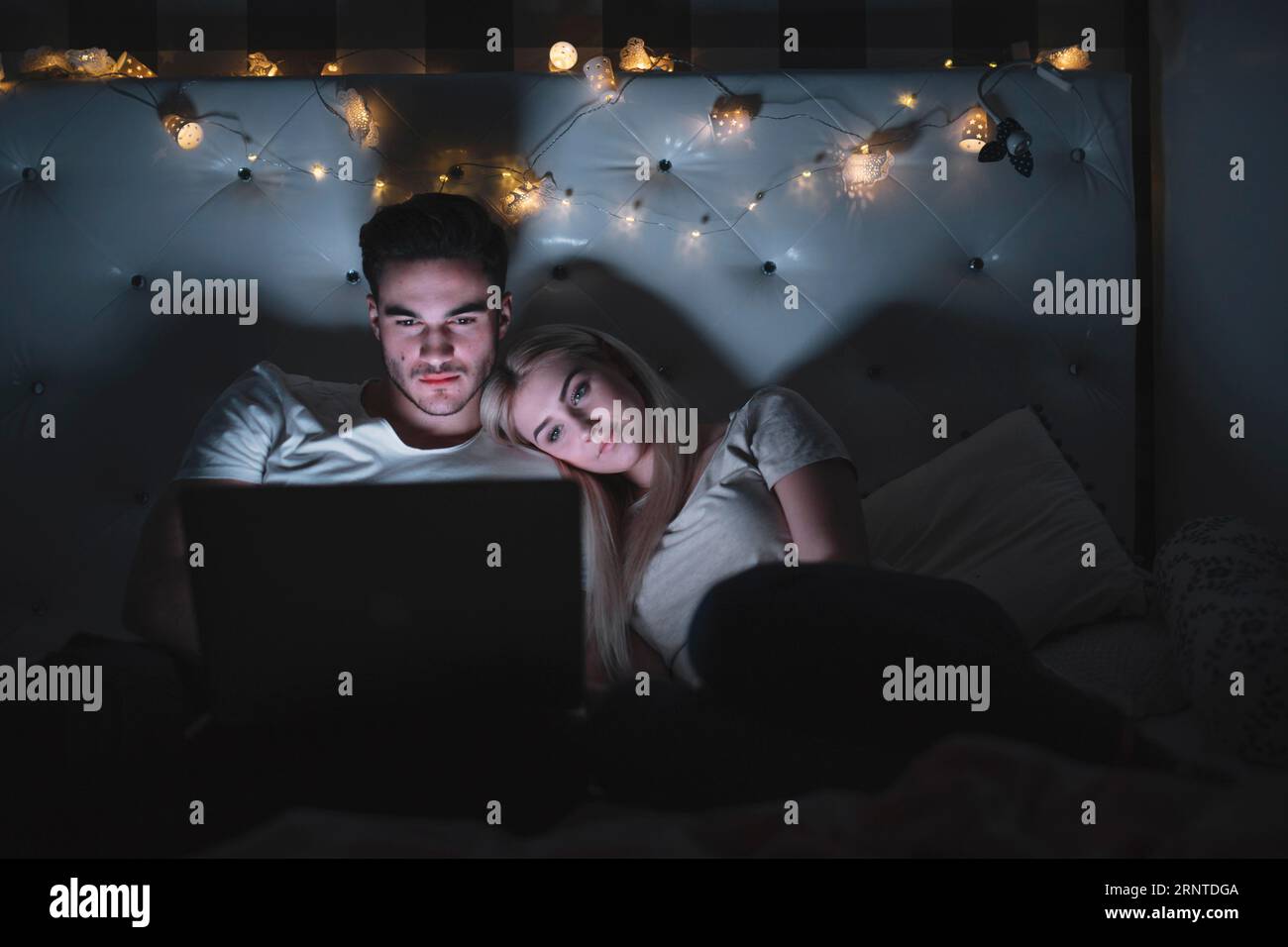Couple watching movie bed Stock Photo - Alamy