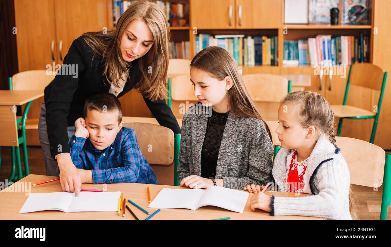 Female teacher helping pupils studying process Stock Photo - Alamy