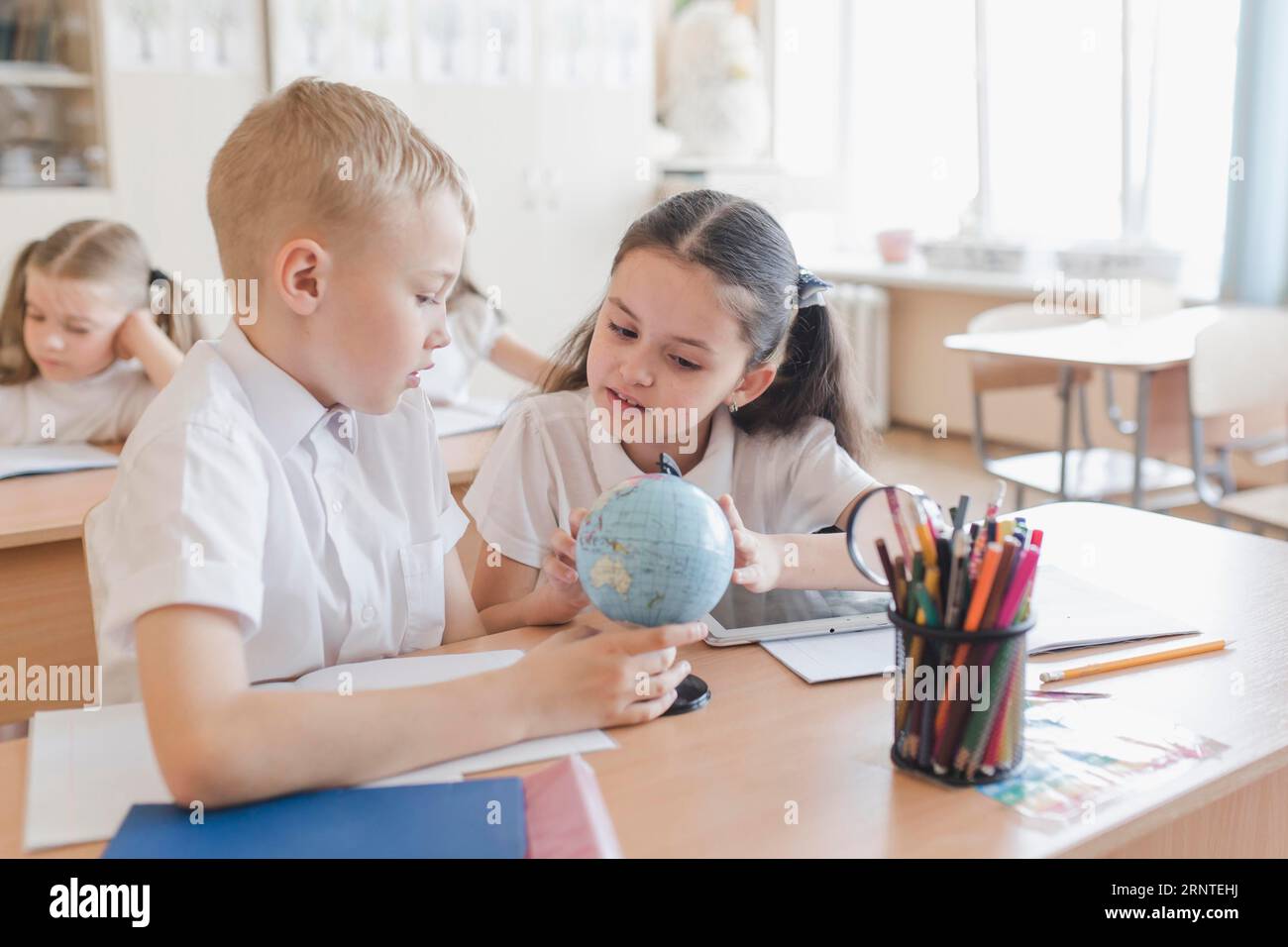 Kids examining globe lesson Stock Photo - Alamy
