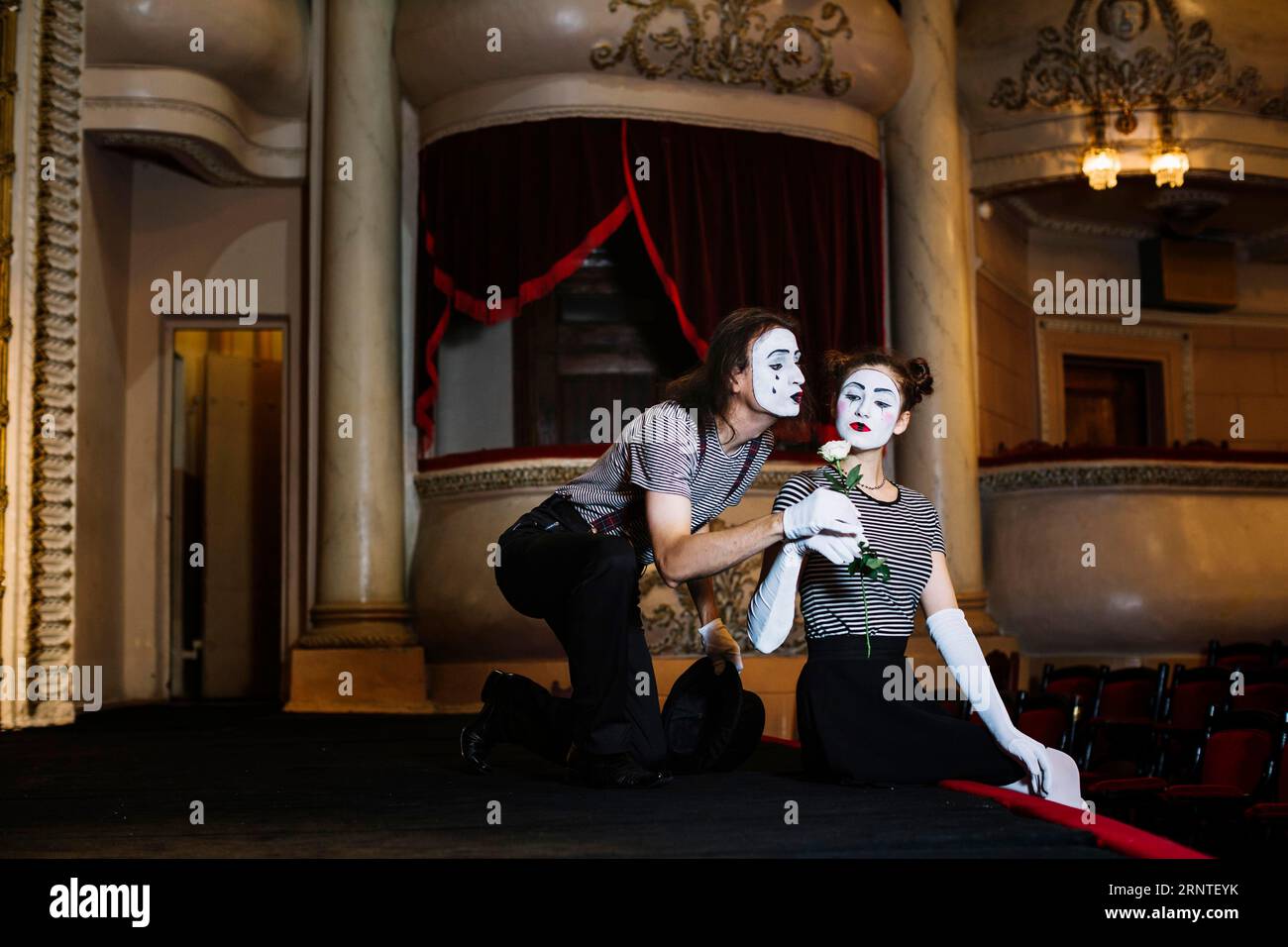 Male mime artist giving white rose female mime sitting stage Stock ...