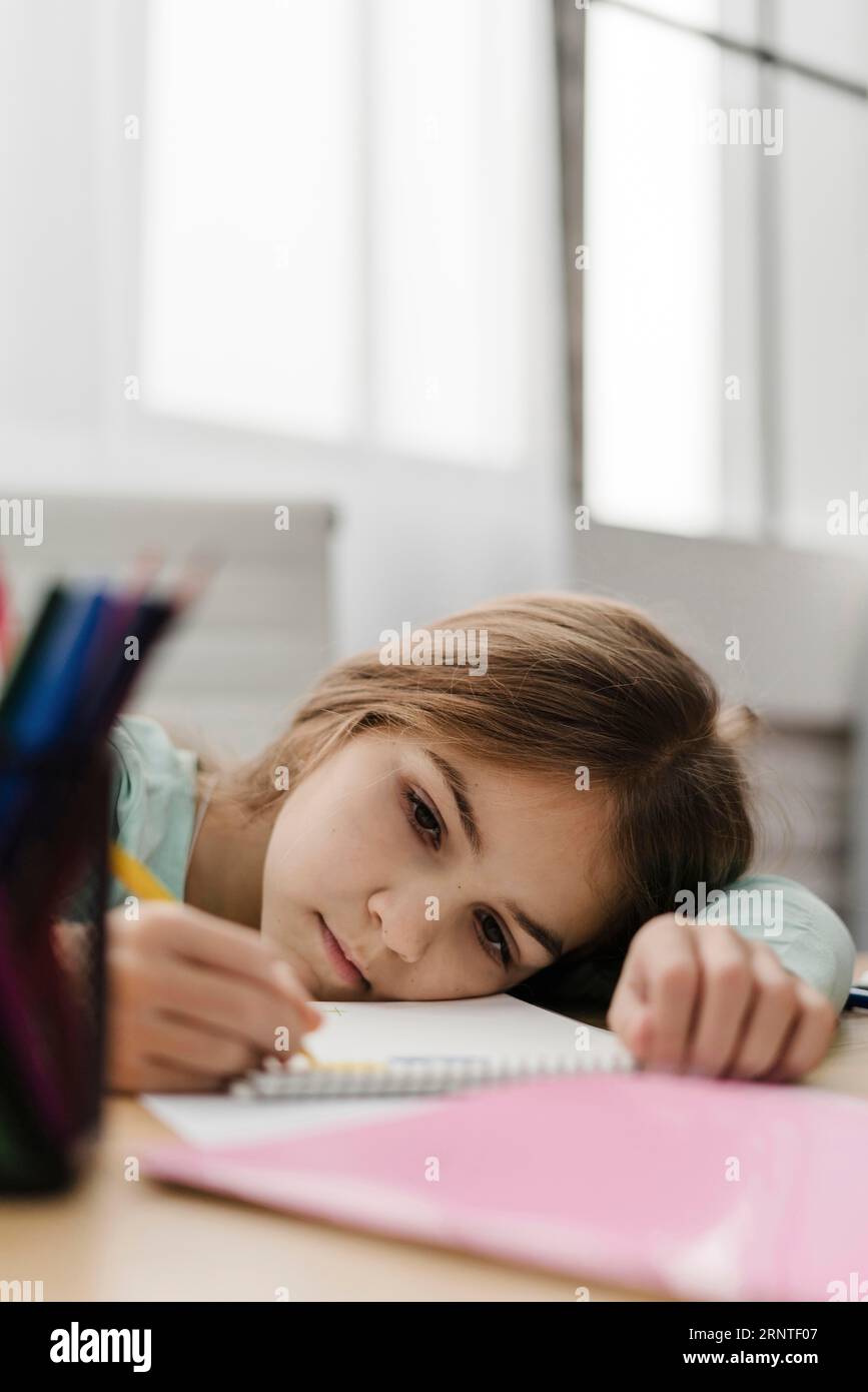 Little girl taking notes while being bored Stock Photo - Alamy