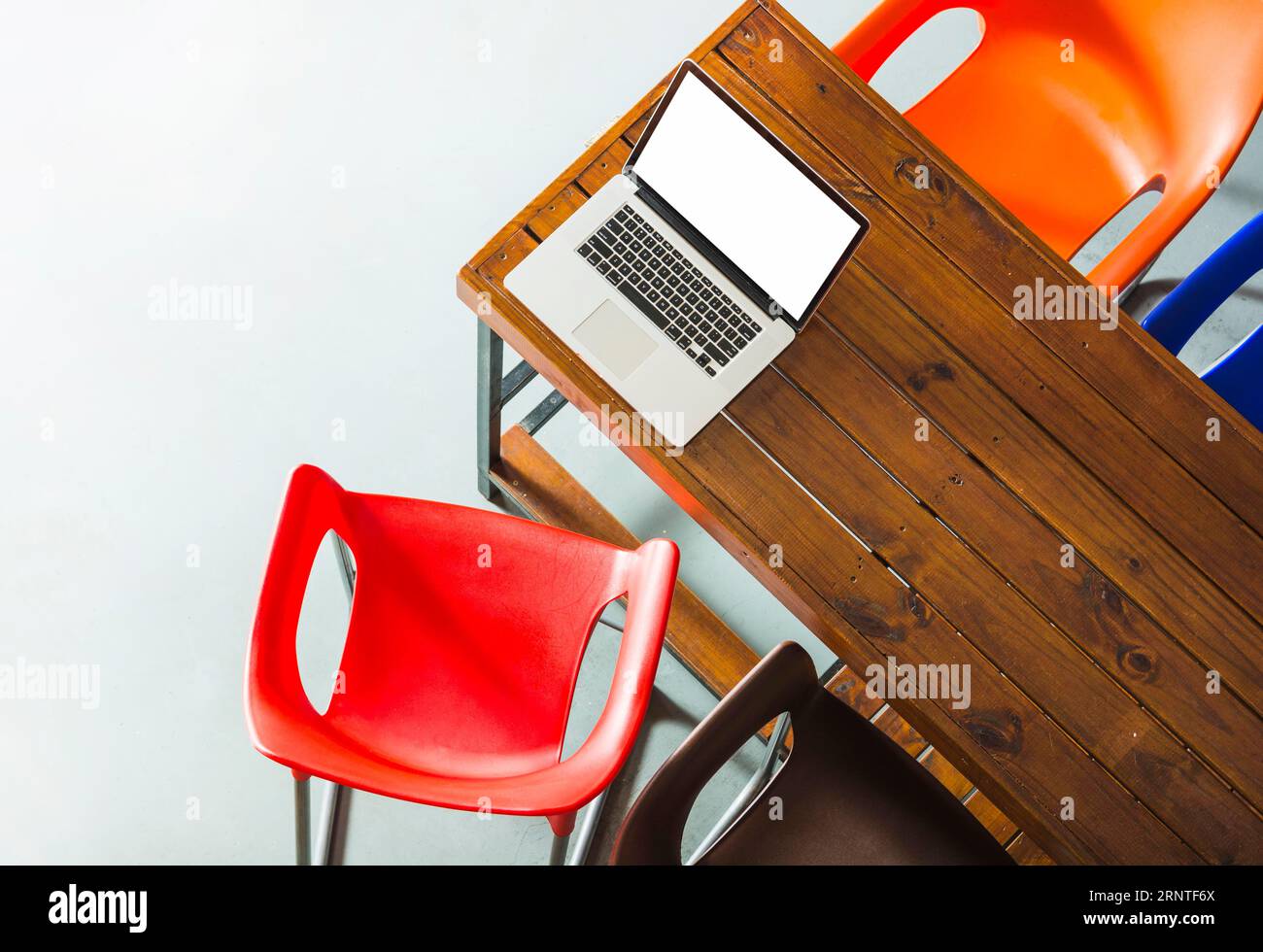Overhead view open laptop wooden table with colorful chairs Stock Photo ...