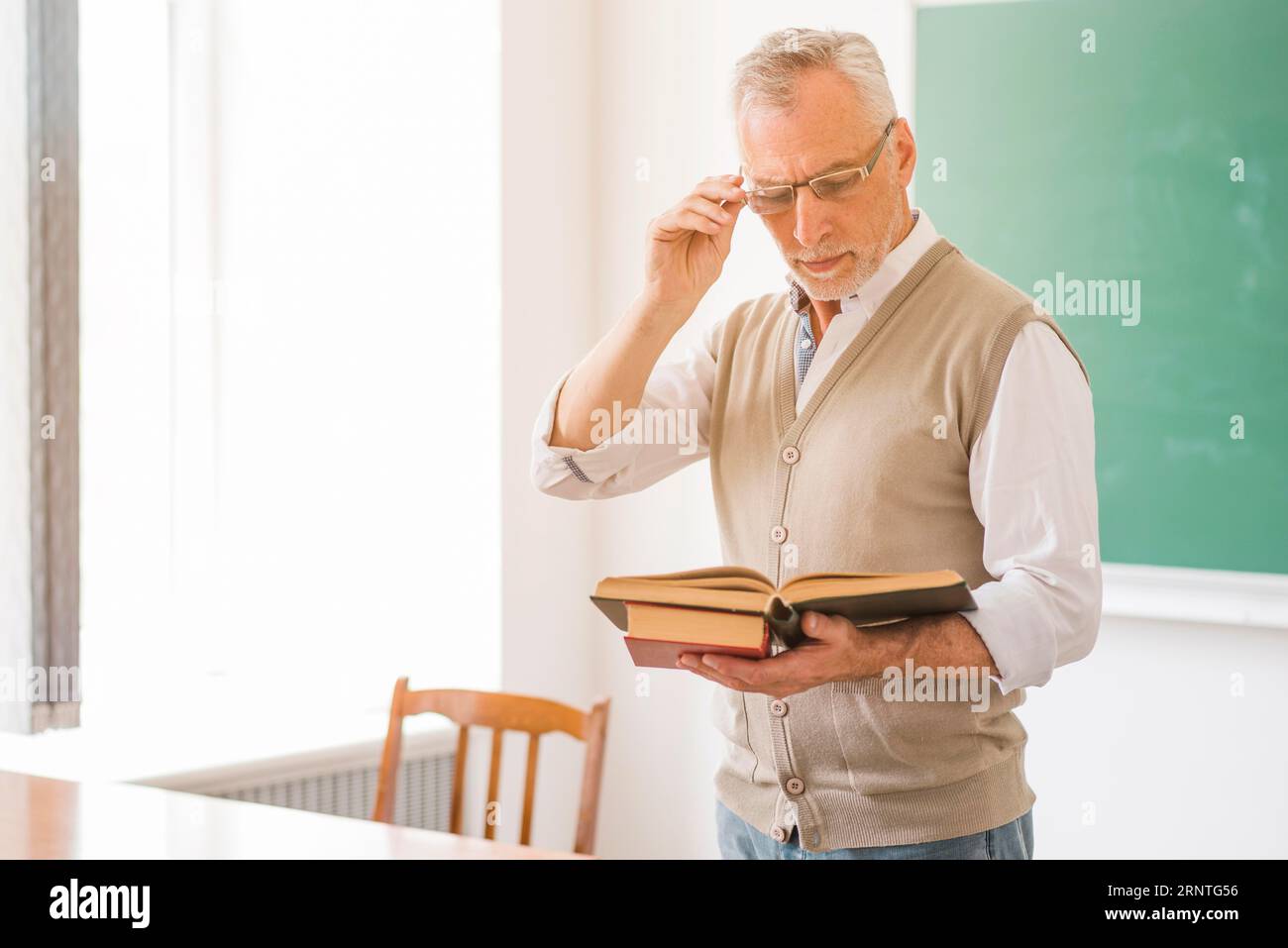 Focused male professor glasses reading book classroom Stock Photo - Alamy