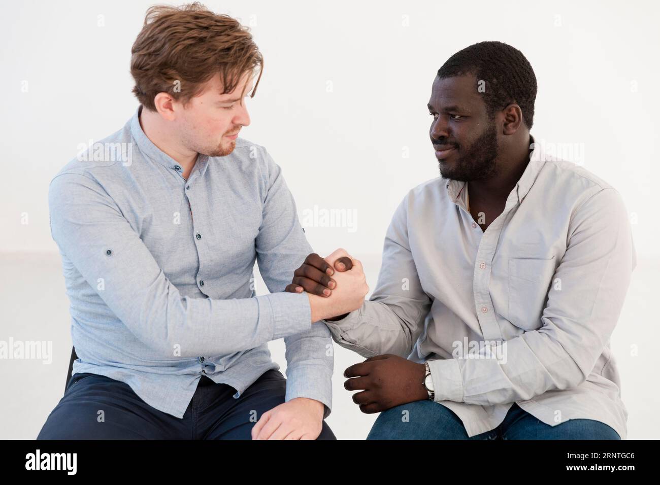 Front view men holding hands consoling each other Stock Photo - Alamy