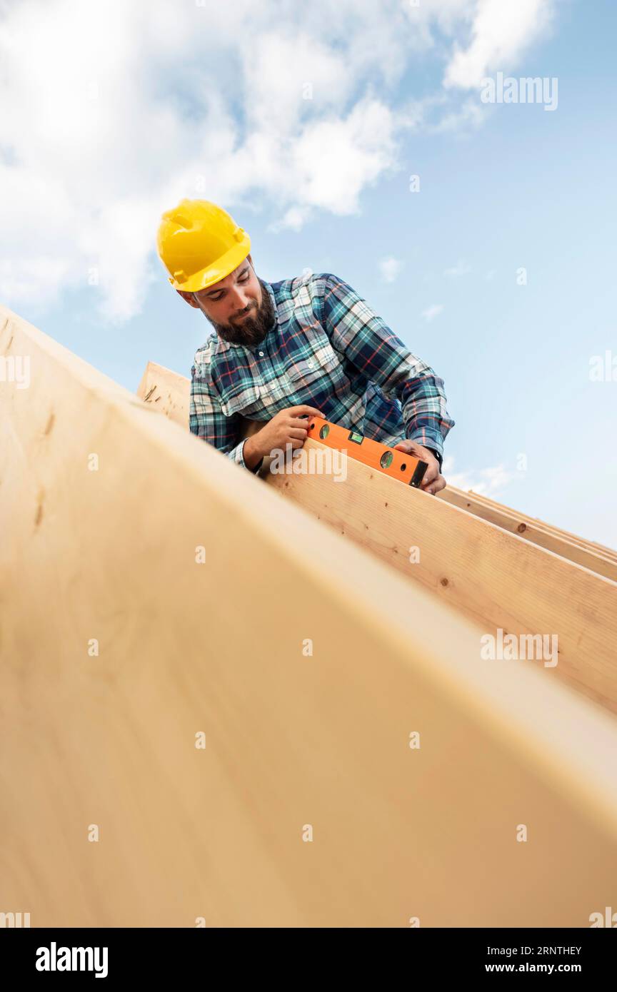 Worker with hard hat level checking roof timber house Stock Photo - Alamy