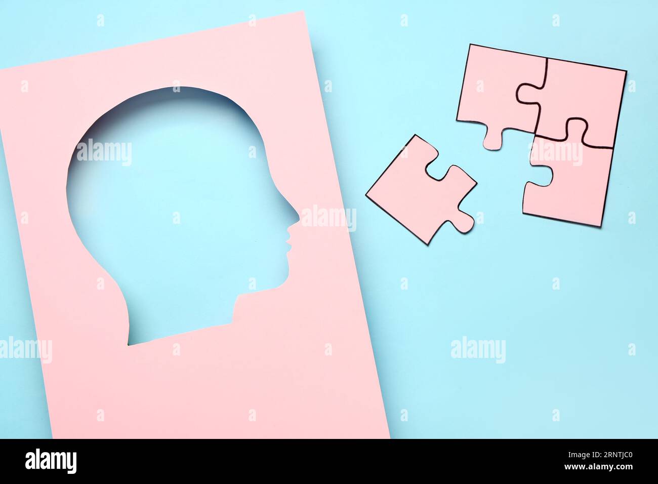 Cut pink paper in shape of human head with puzzle pieces on blue ...