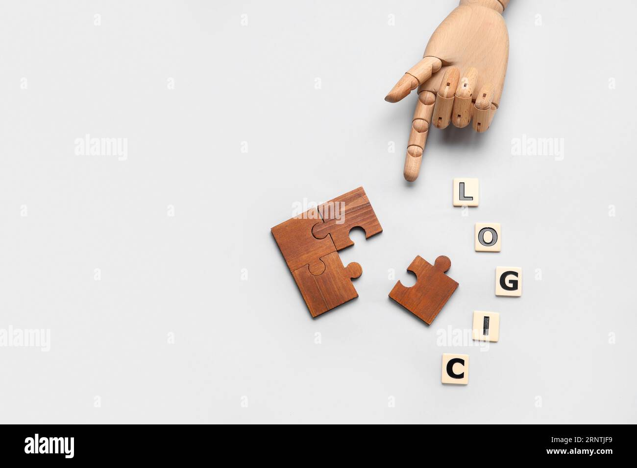 Wooden hand with puzzle pieces and word LOGIC on white background Stock ...