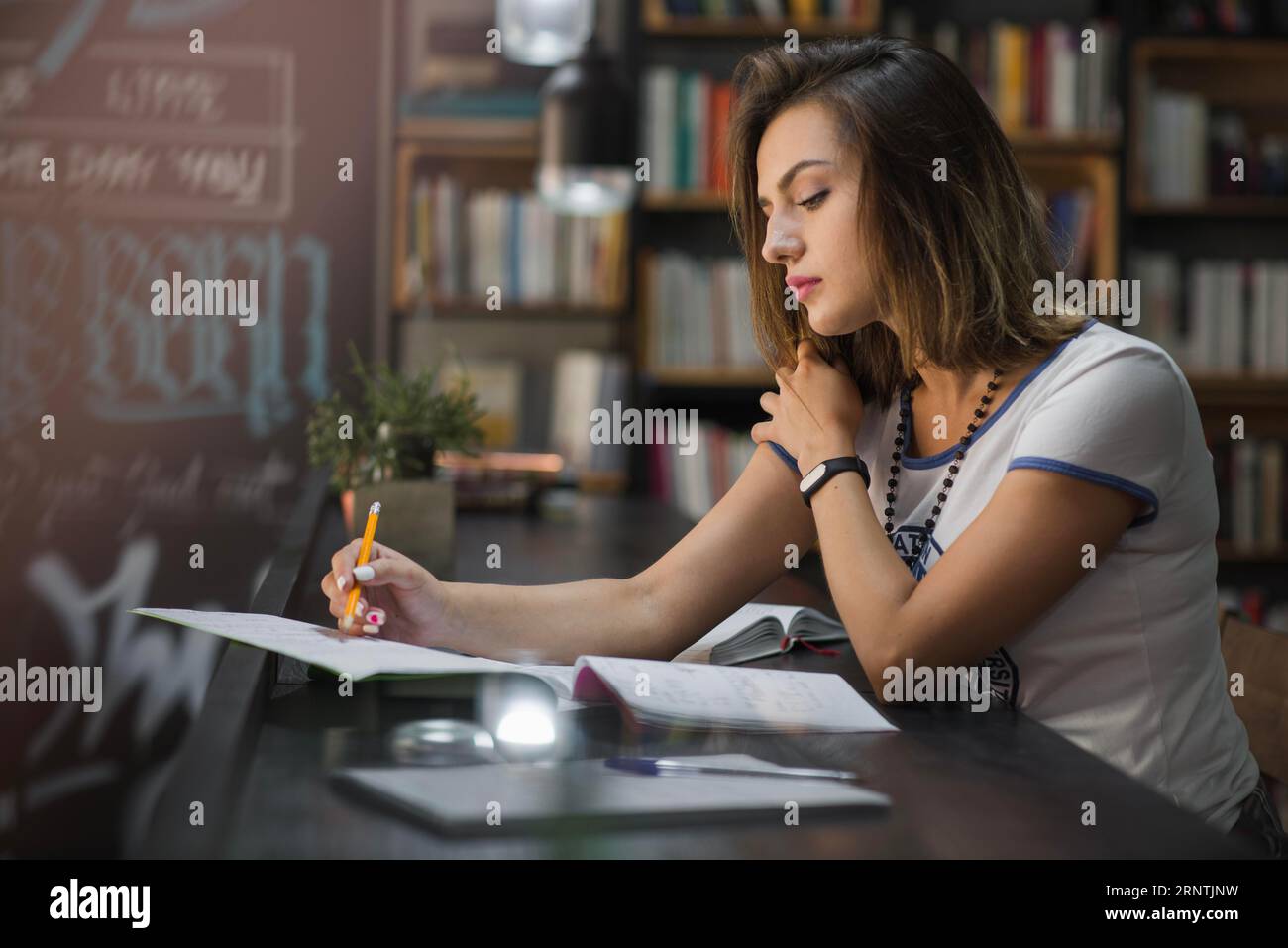 Girl sitting table with notebooks writing Stock Photo - Alamy