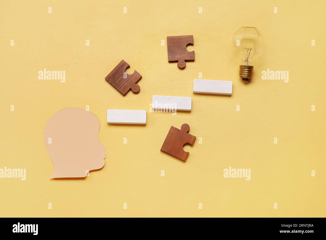 Paper human head with blocks, puzzle pieces and light bulb on yellow ...