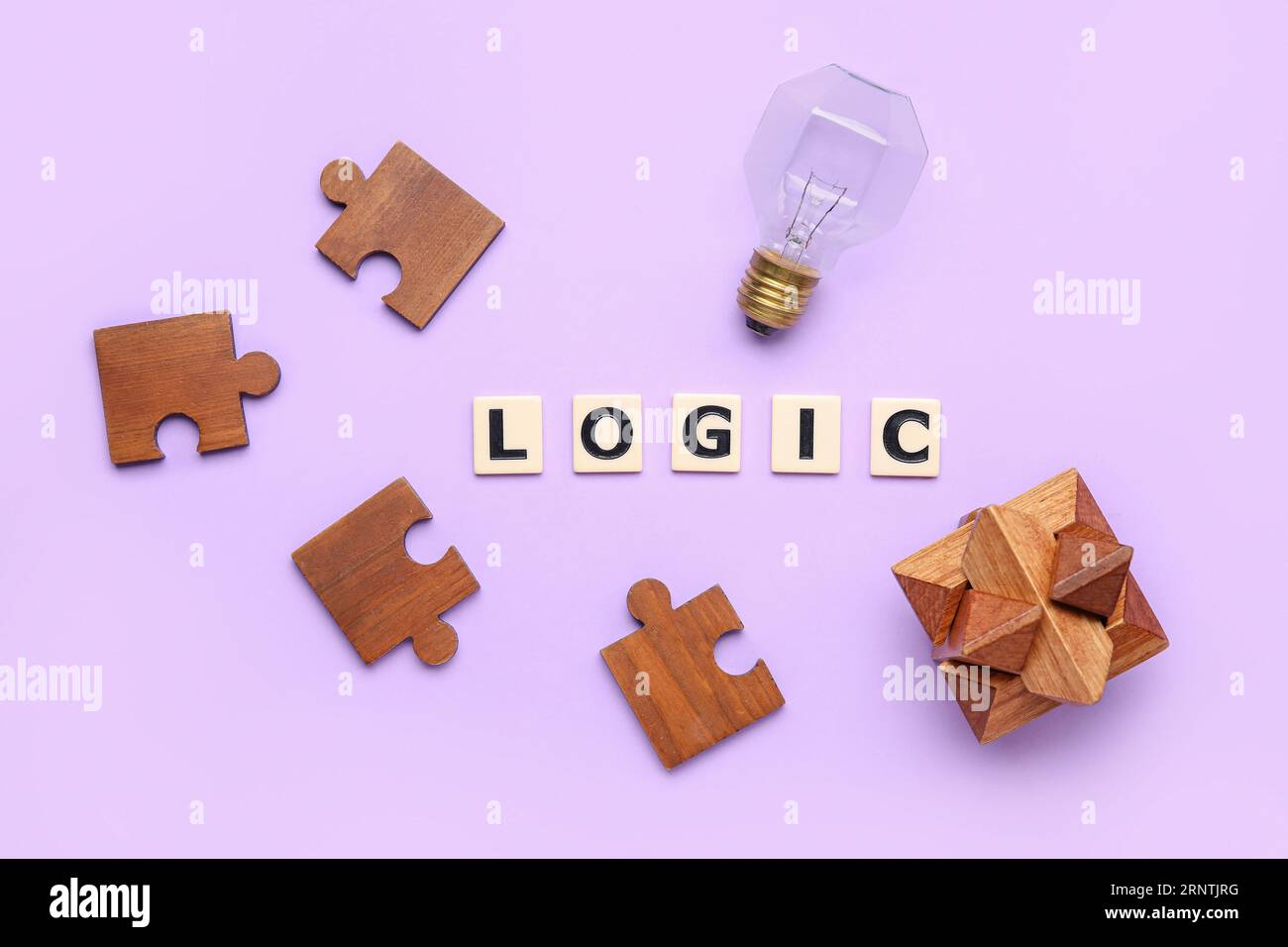 Word LOGIC with light bulb, wooden toy and puzzle pieces on lilac ...