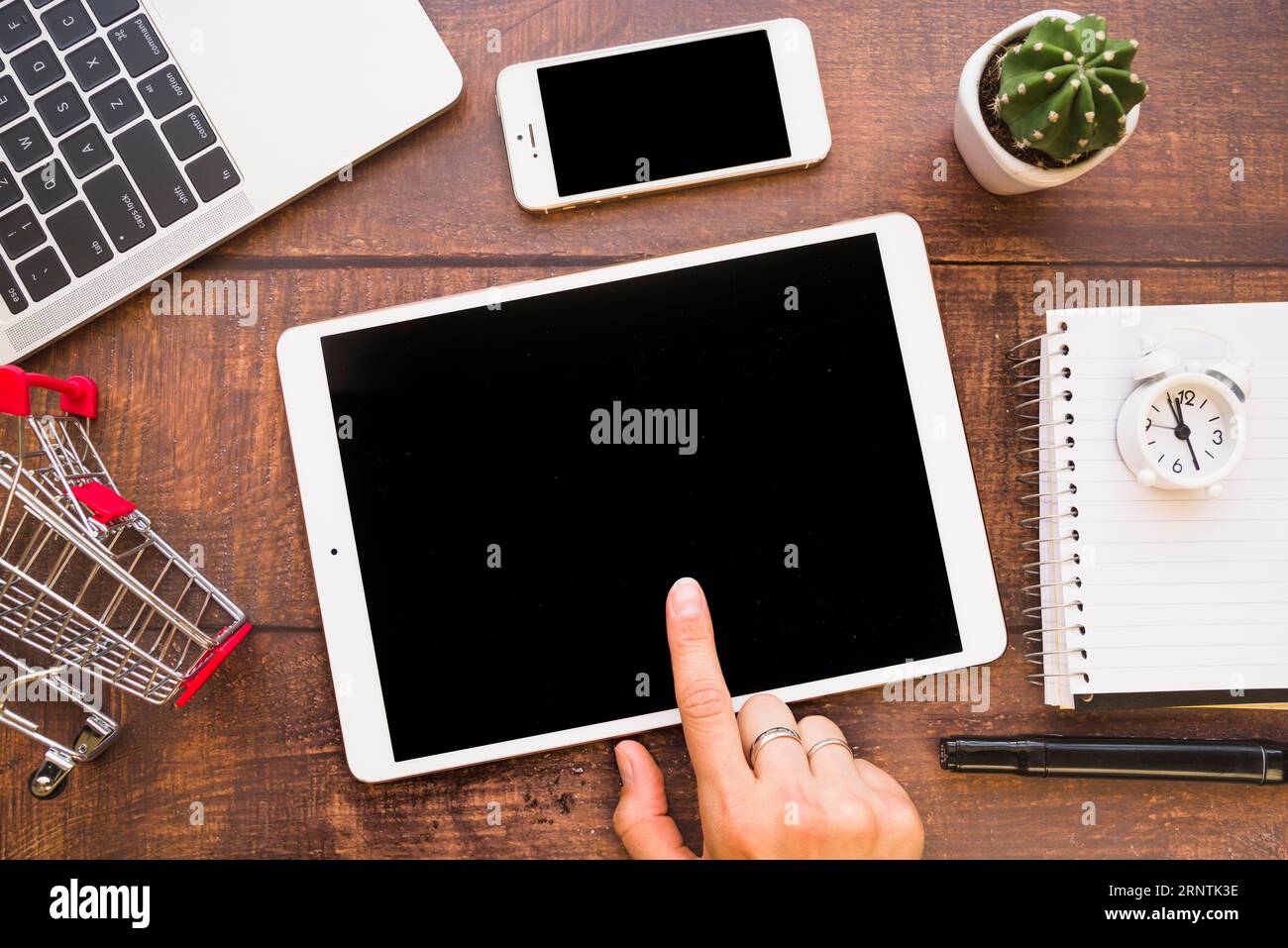 Hand tablet near smartphone laptop shopping trolley Stock Photo - Alamy