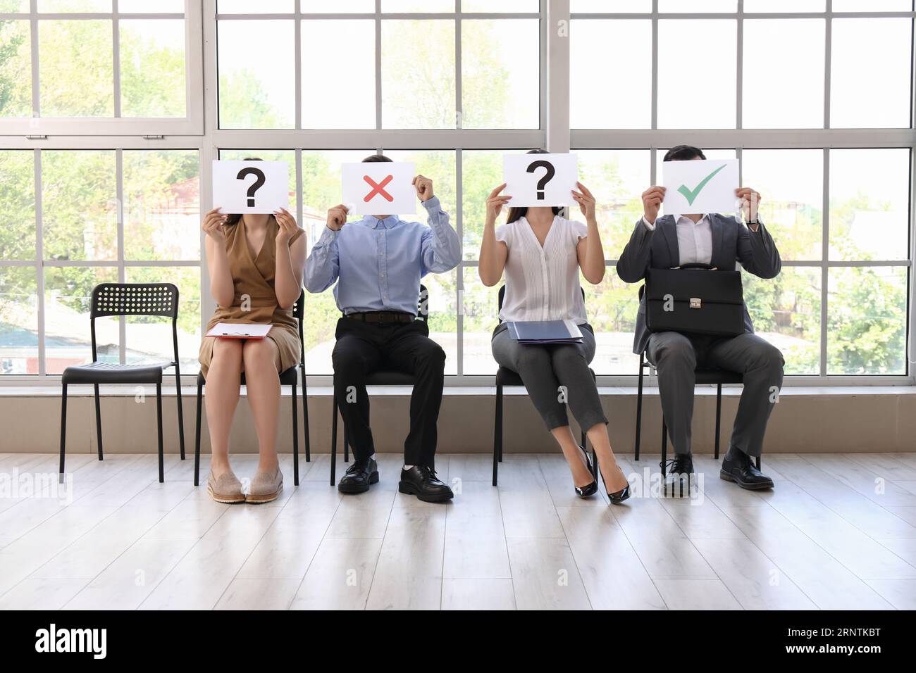 Young people holding paper sheets with different marks while waiting ...