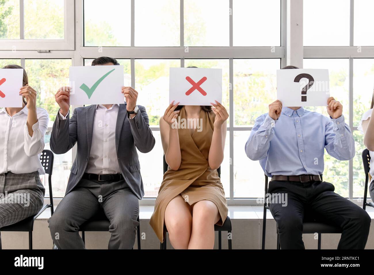 Young people holding paper sheets with different marks while waiting ...