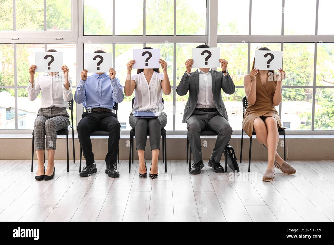 Young people holding paper sheets with question marks while waiting for ...