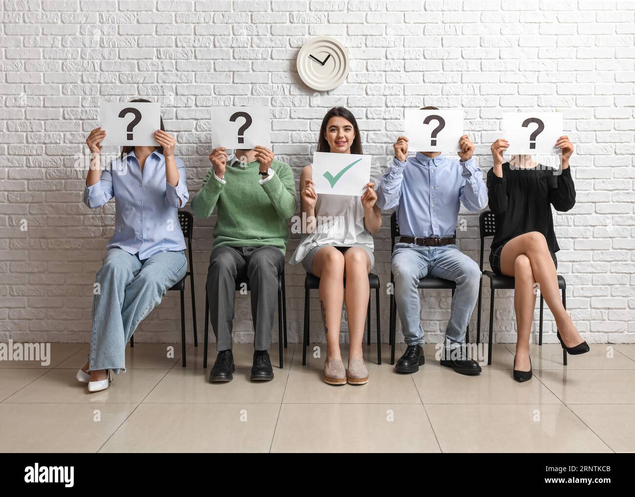 Young people holding paper sheets with check and question marks while ...