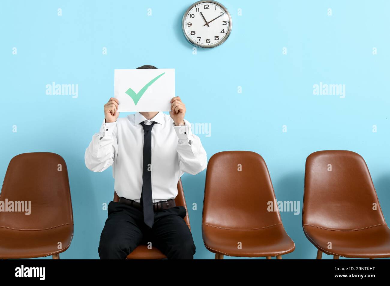 Male applicant holding paper with check mark in room Stock Photo - Alamy
