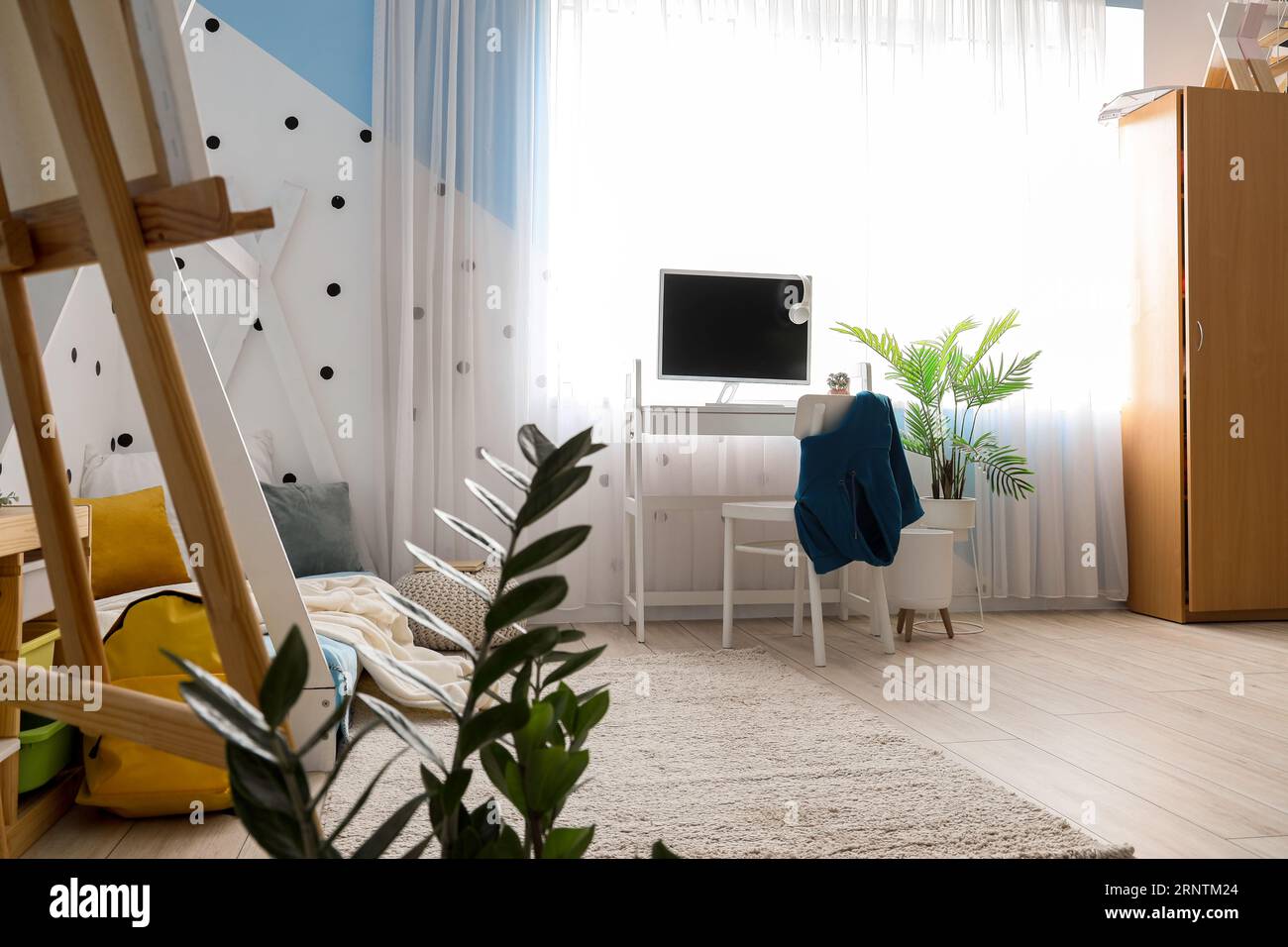 Interior of children's bedroom with cozy bed, easel and modern computer ...