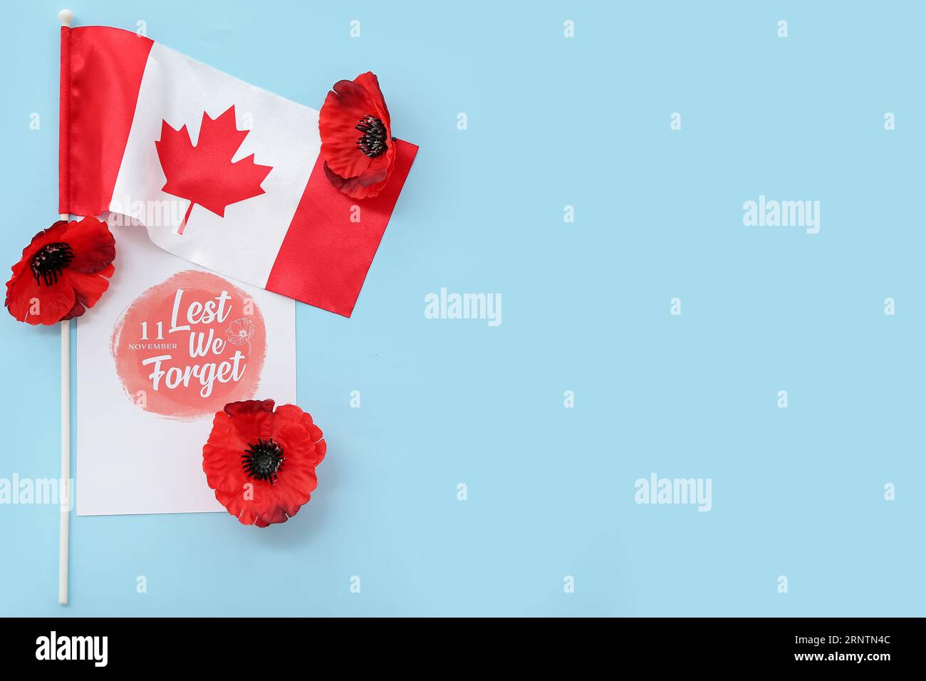 Poppy flowers, flag of Canada and card with text LEST WE FORGET on blue ...