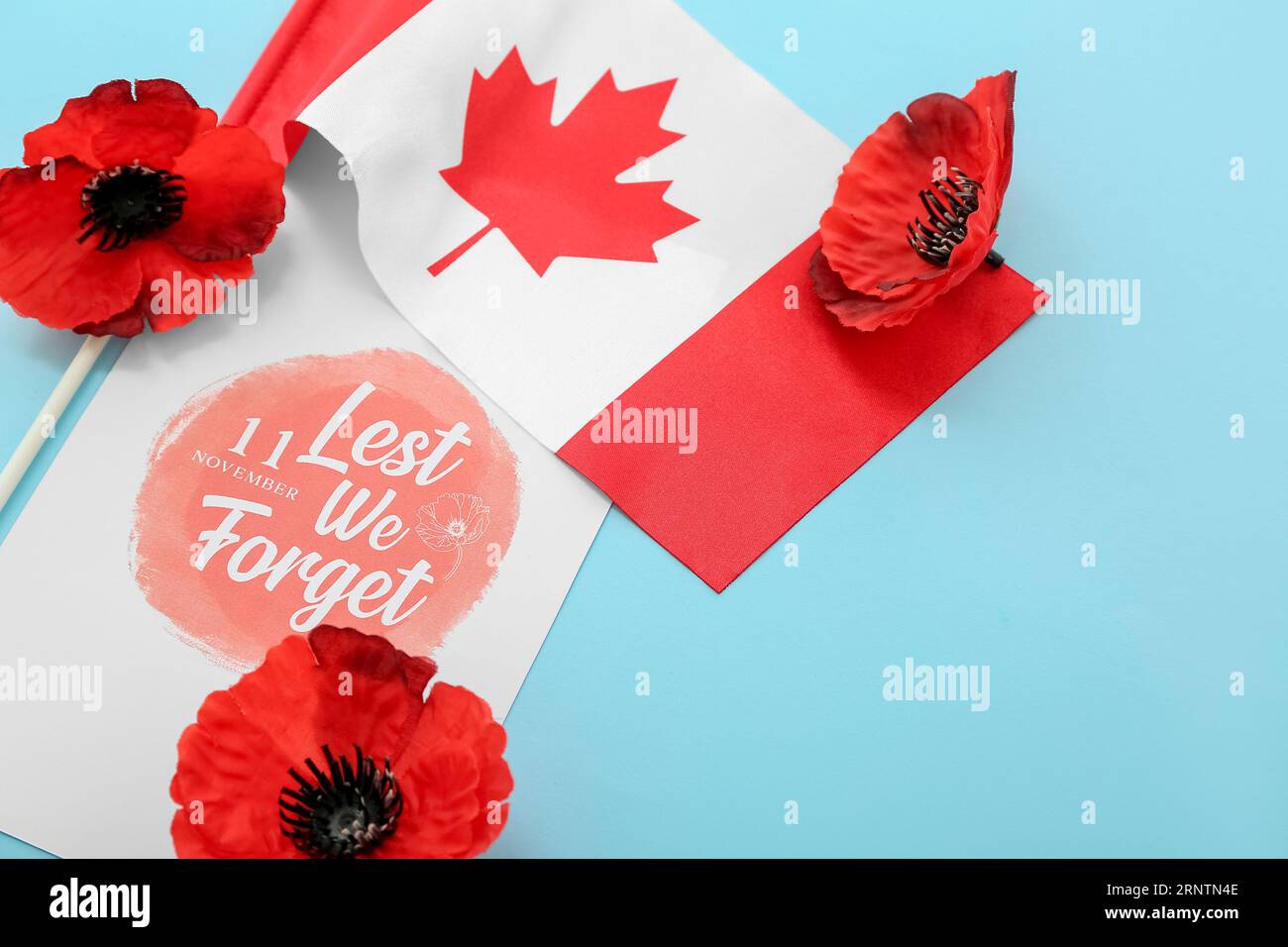 Poppy flowers, flag of Canada and card with text LEST WE FORGET on blue ...