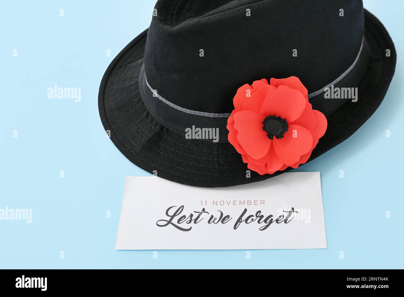Poppy flower, hat and card with text LEST WE FORGET on blue background ...