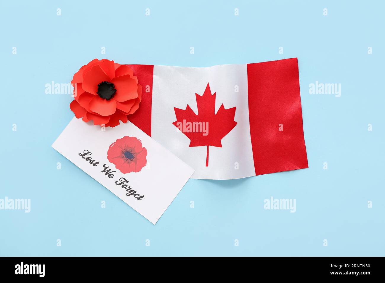 Poppy flowers, flag of Canada and card with text LEST WE FORGET on blue ...
