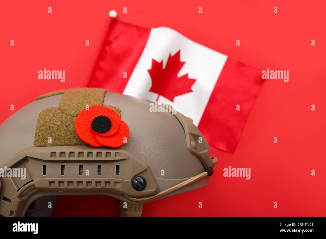 Military helmet with poppy flower and flag of Canada on red background ...