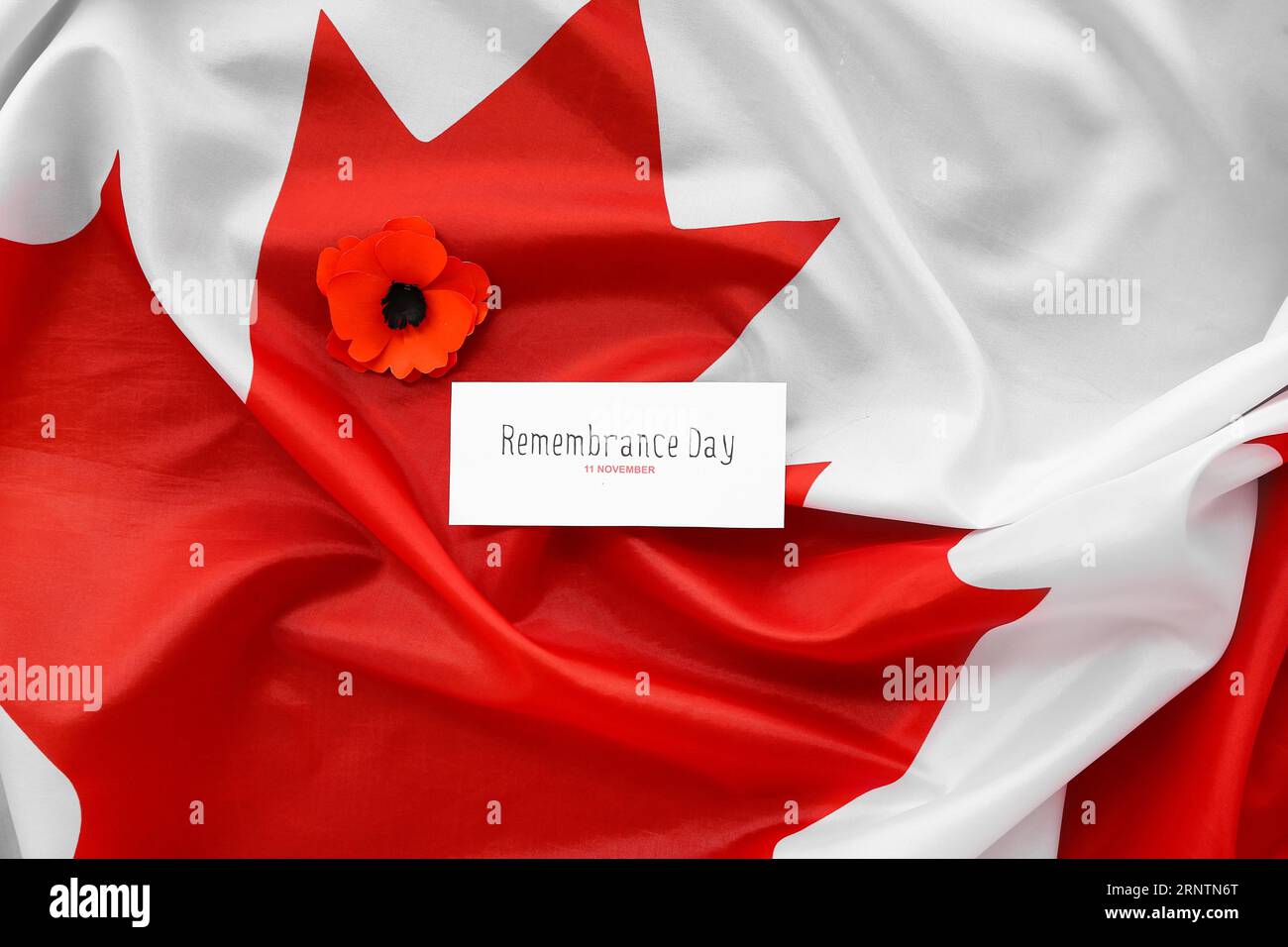 Poppy flower and card on flag of Canada as background. Remembrance Day ...