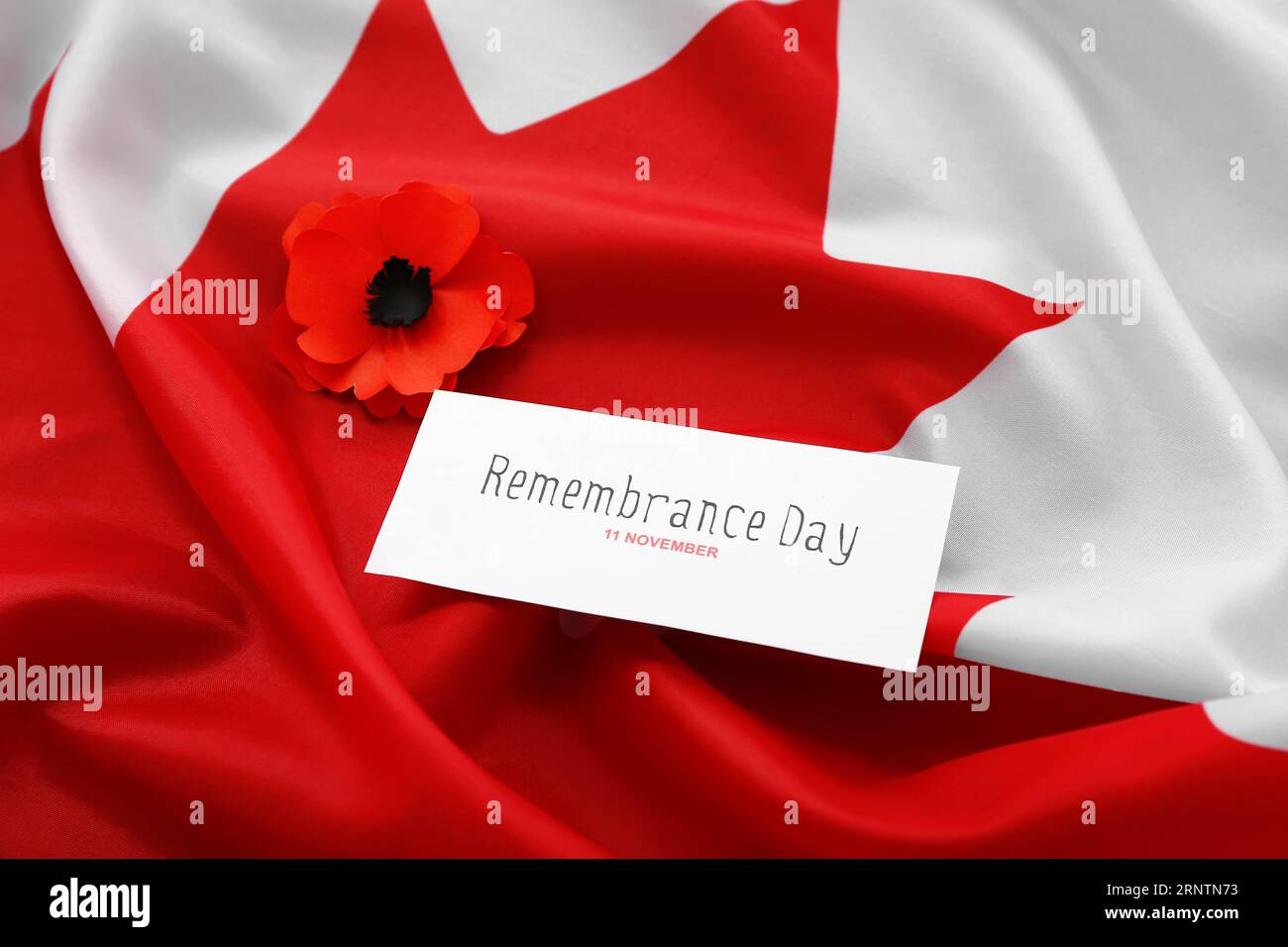 Poppy flower and card on flag of Canada as background. Remembrance Day ...