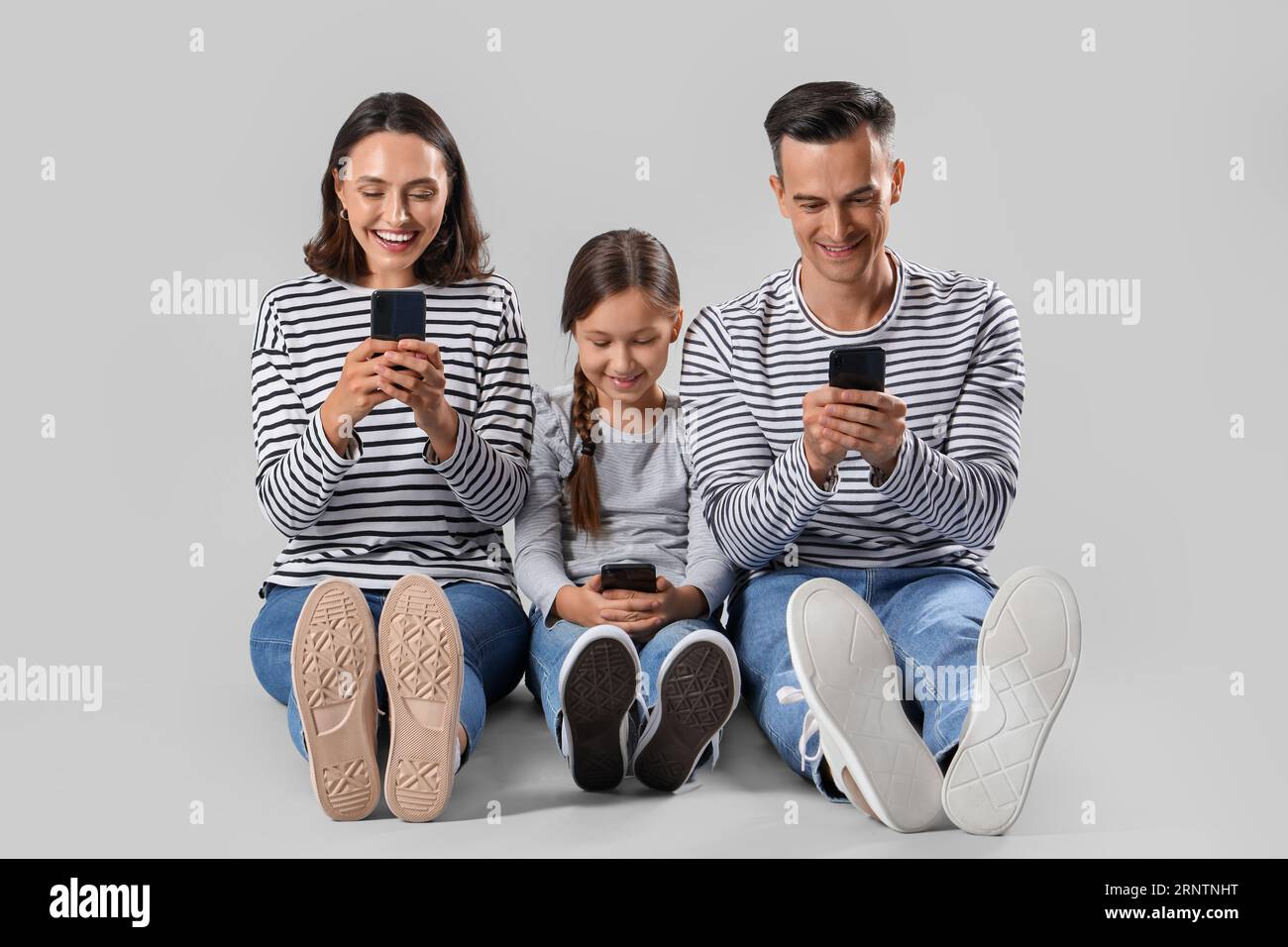 Happy family with mobile phones on grey background Stock Photo - Alamy