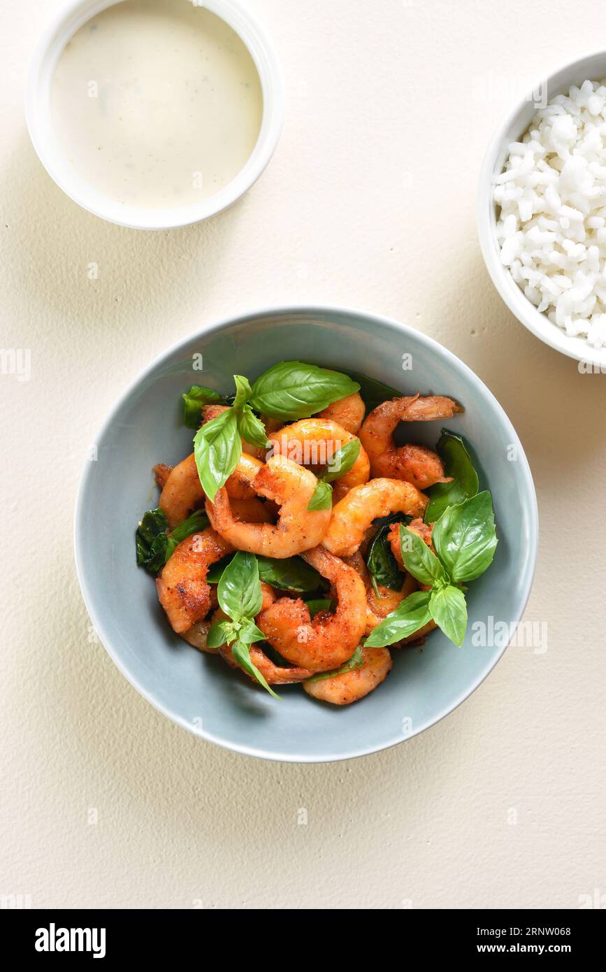Roasted prawn with basil leaves in bowl over light stone background ...