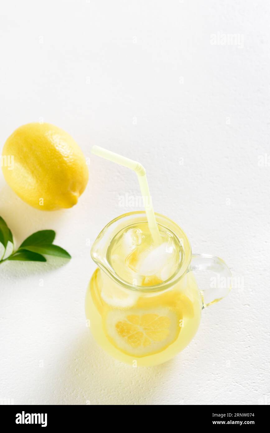 Lemon lemonade in glass pitcher on white background with free space ...