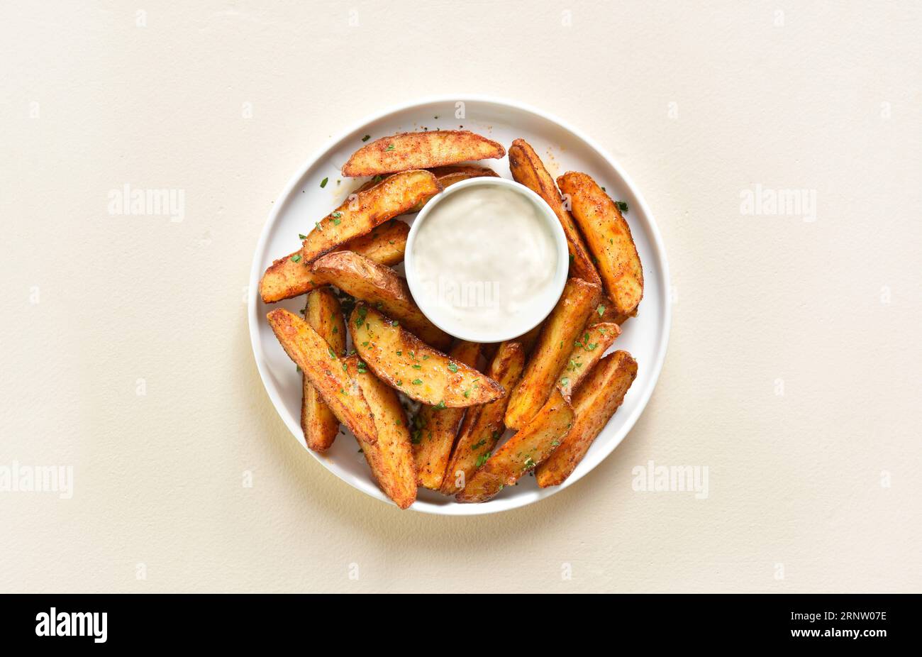 Oven baked potato wedges with sauce over light stone background. Top ...