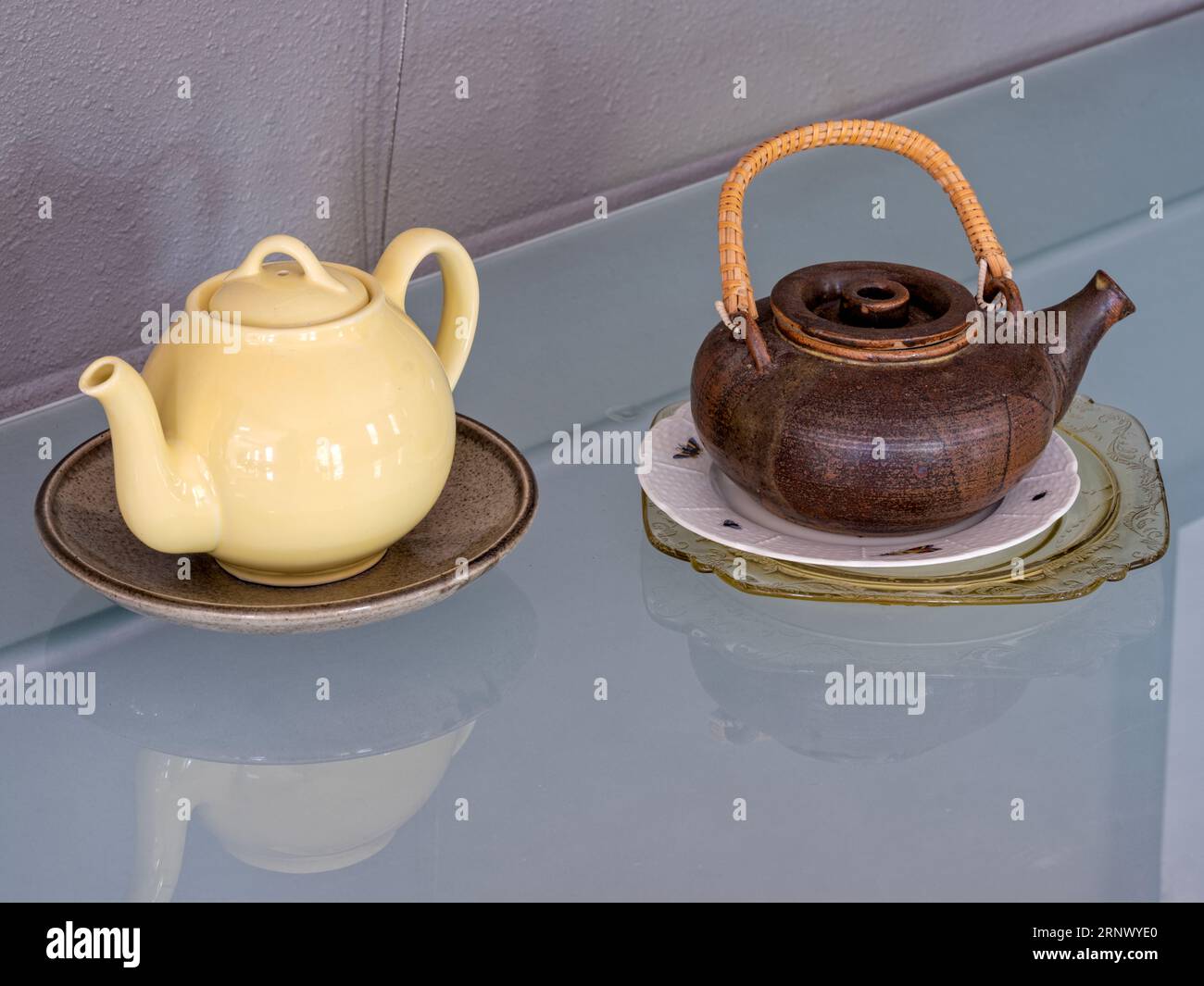 Two teapots in their saucers on a glass table Stock Photo - Alamy