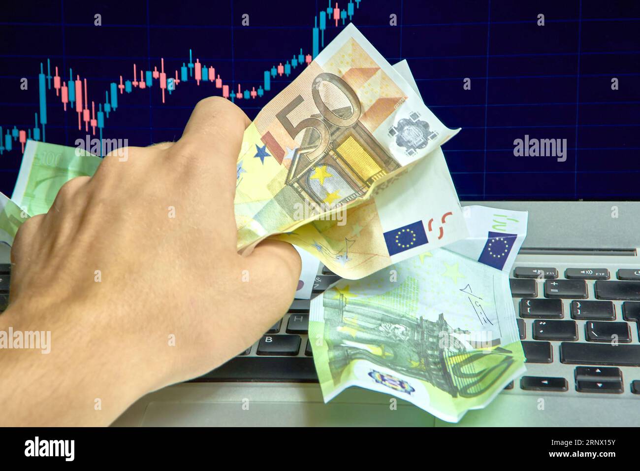 A hand forcefully clutching paper bills, on the background of the stock ...