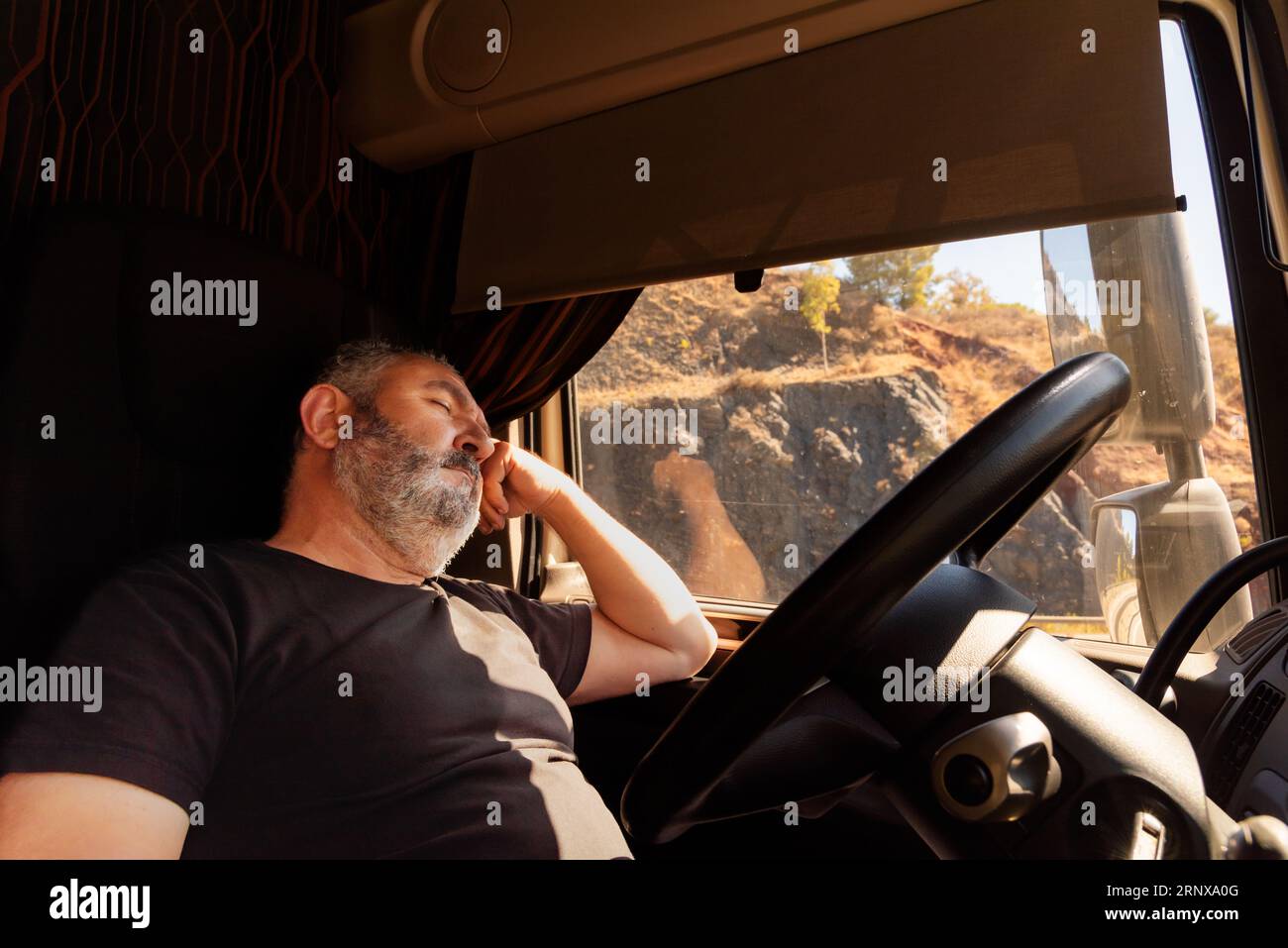 Truck driver resting in the seat of the truck while waiting to load ...