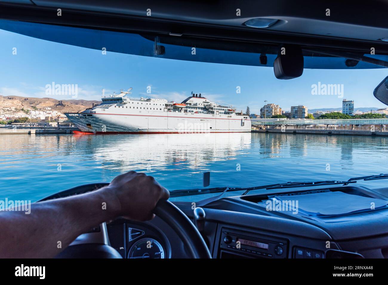 View of a ferry docked in port from the cabin of a truck as it turns ...