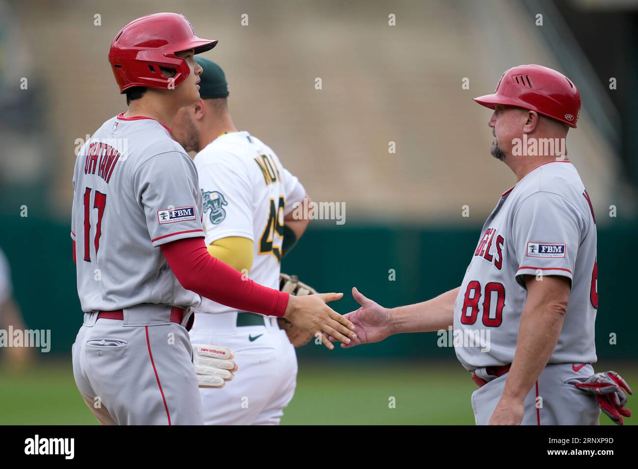Los Angeles Angels' Shohei Ohtani, left, is greeted by first base coach ...