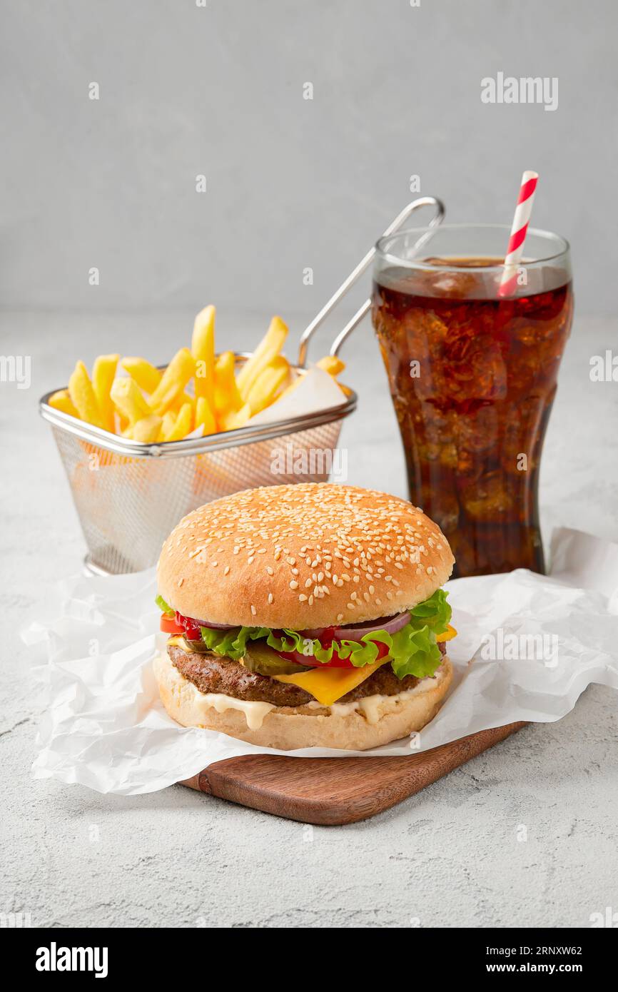 Classic cheeseburger, french fries and soda drink on gray background ...