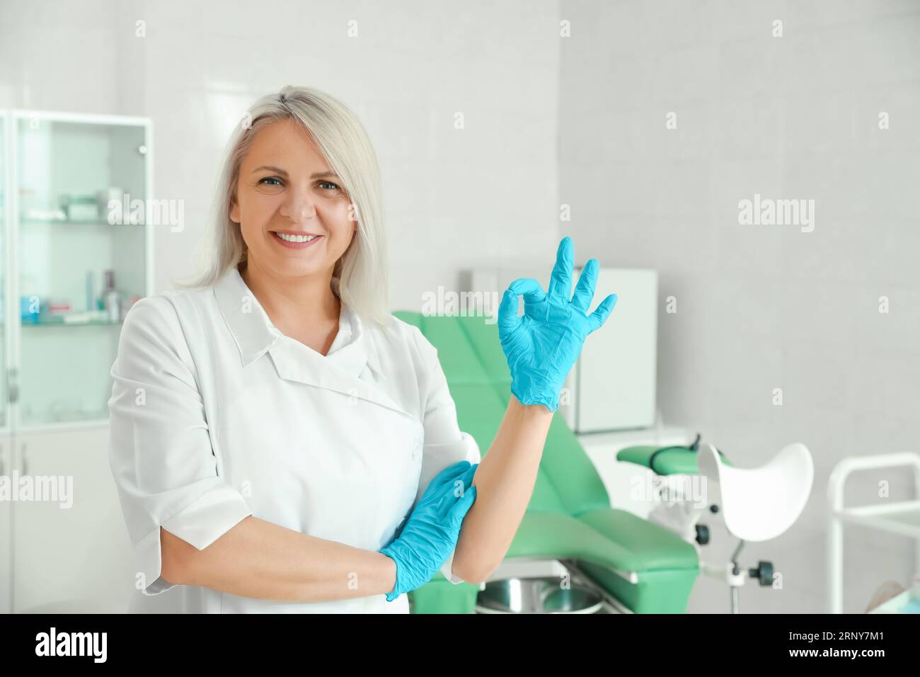 Smiling gynecologist showing OK gesture at workplace in clinic. Space ...