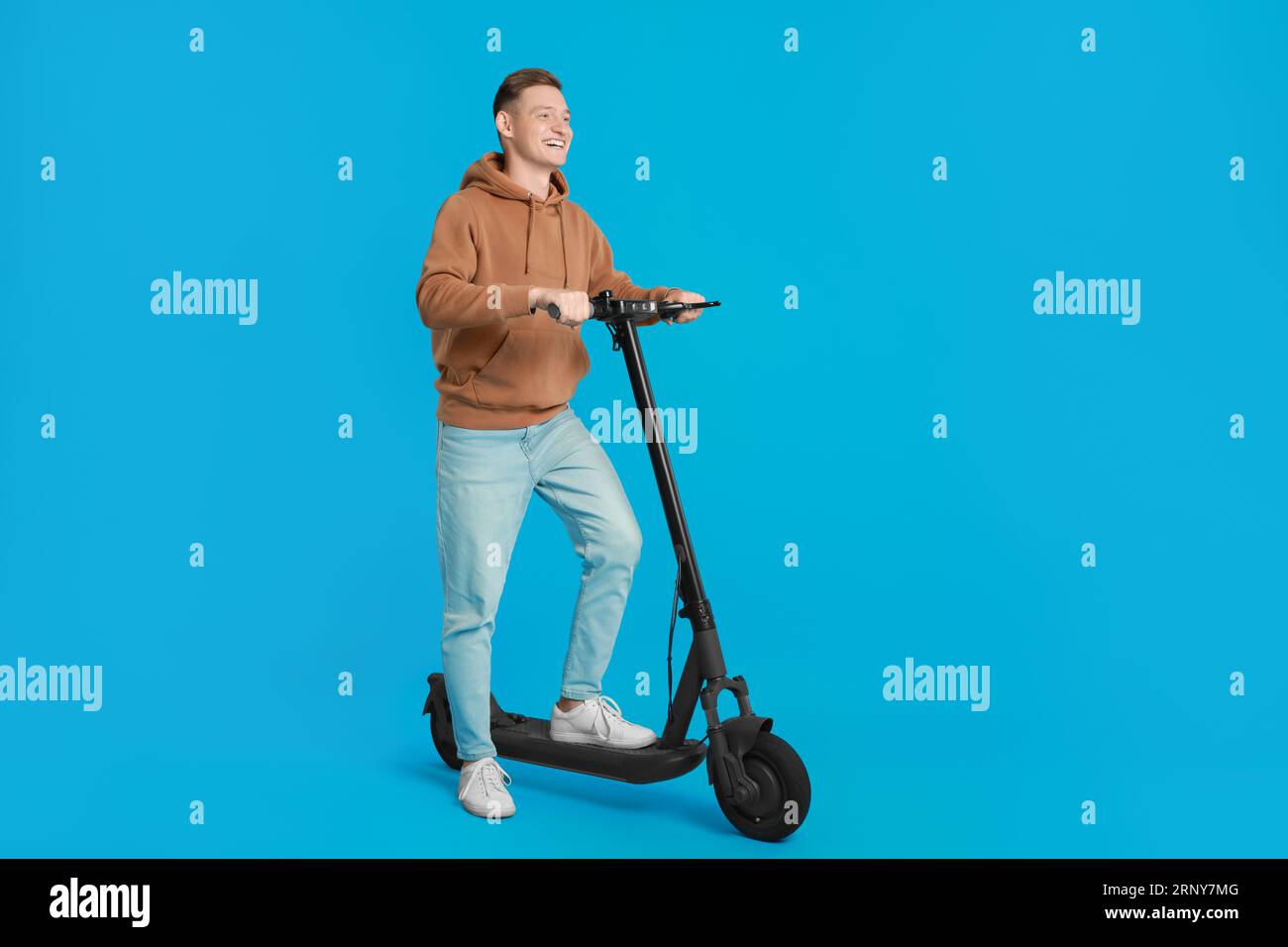 Happy man with modern electric kick scooter on light blue background ...