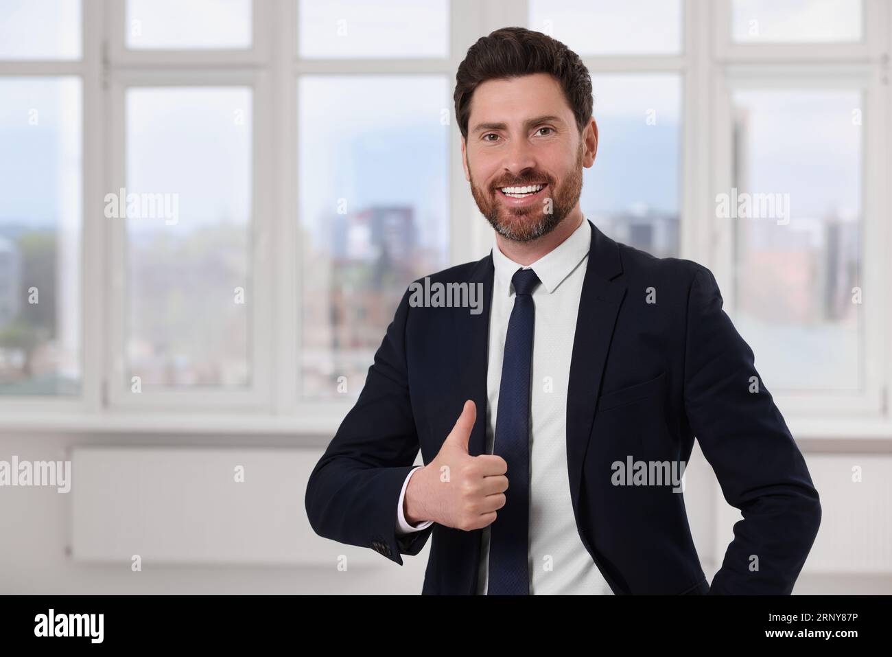 Happy real estate agent showing thumb up in new apartment. Space for ...