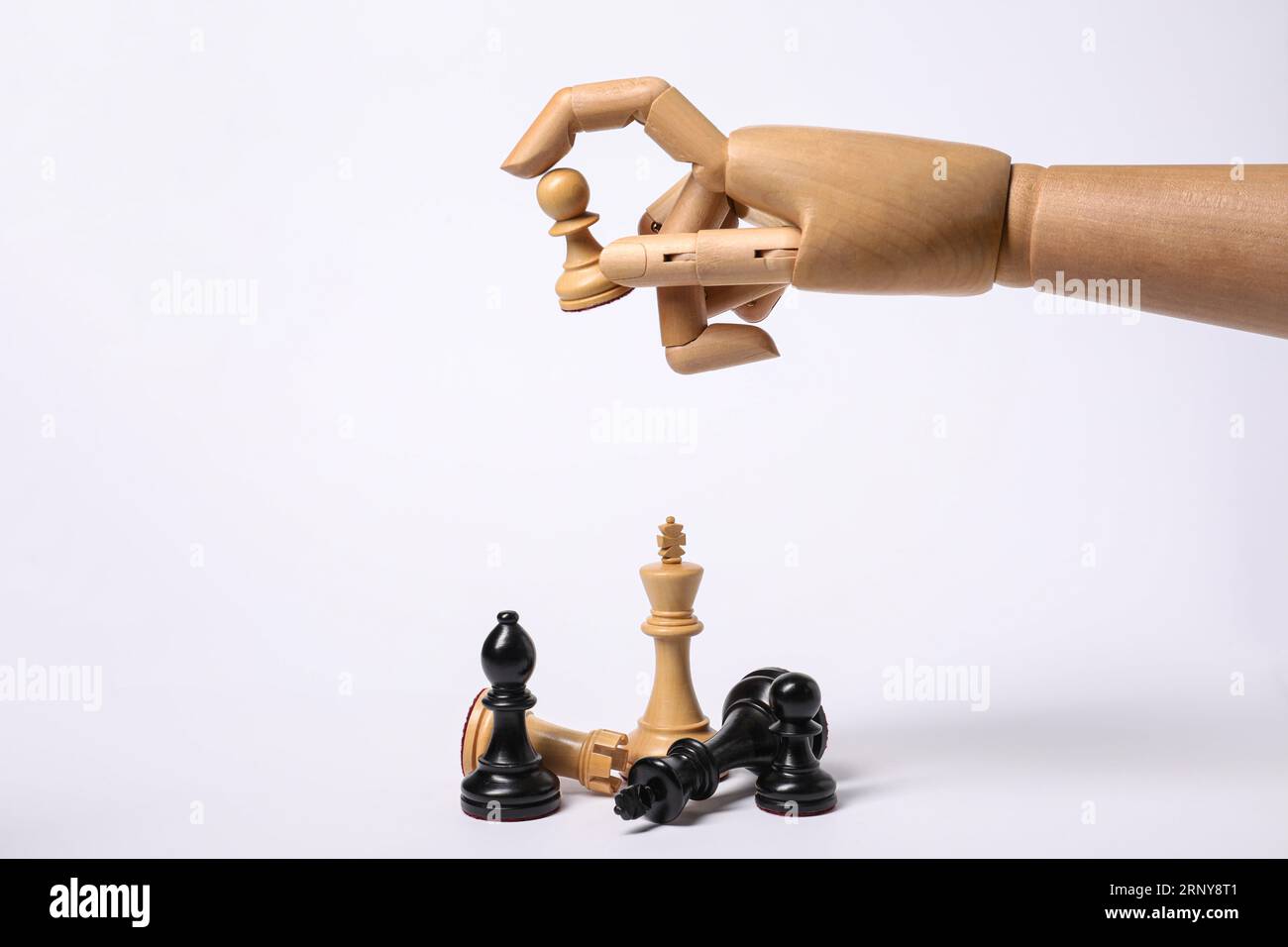 Robot holding pawn over other chess pieces on white background. Wooden ...