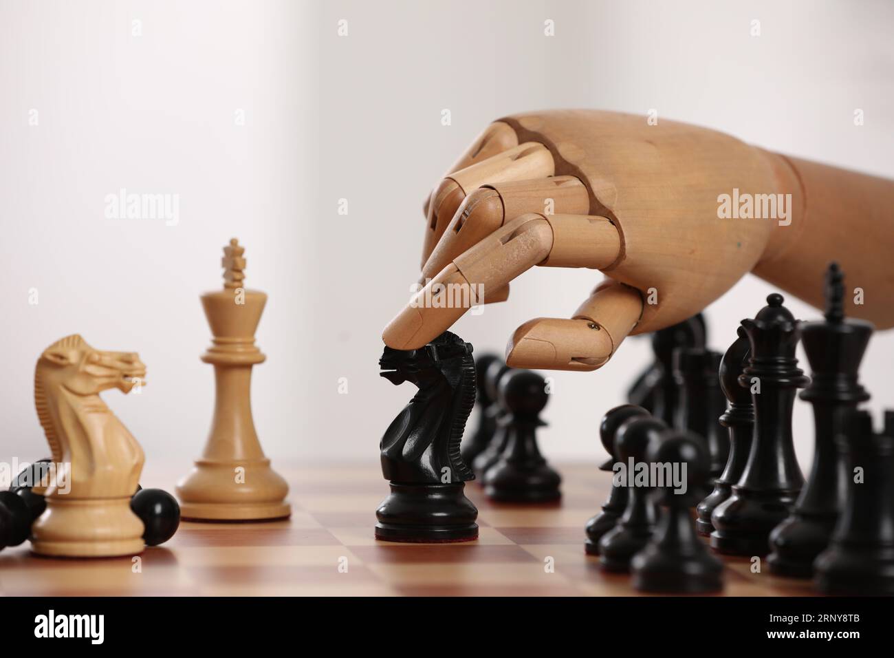 Robot moving chess piece on board against light background, closeup ...